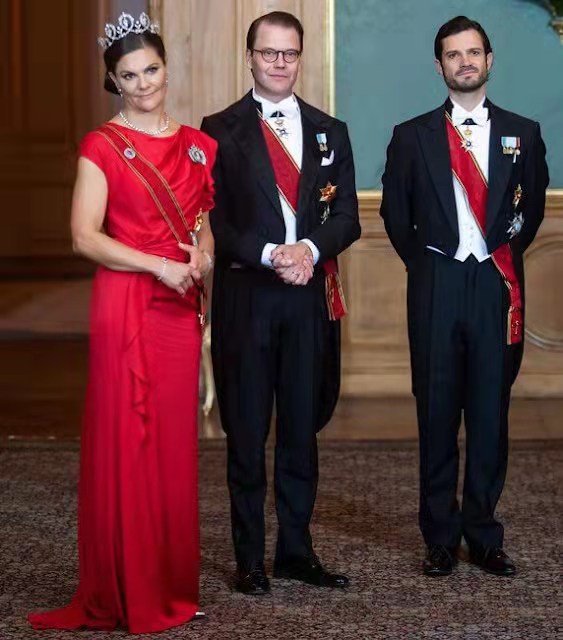 The crown prince of Sweden wears a colorful red dress and a headdress ...
