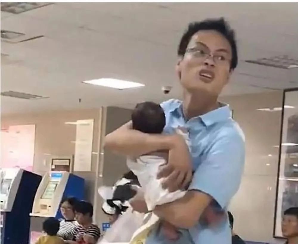 Bao's father hugs his baby in a sling at the hospital, looking at the ...